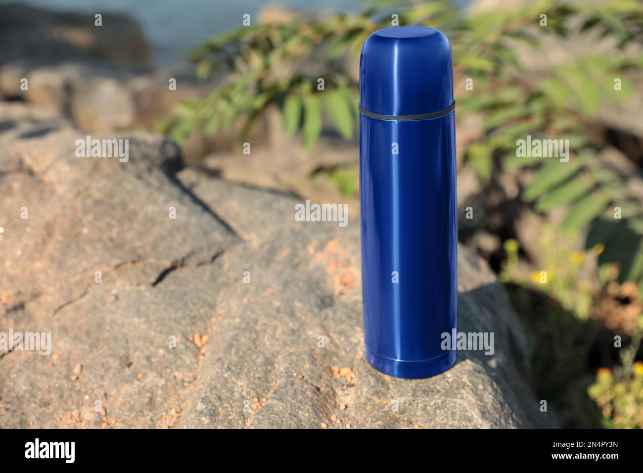 Modern blue thermos on stone near river. Space for text Stock Photo - Alamy