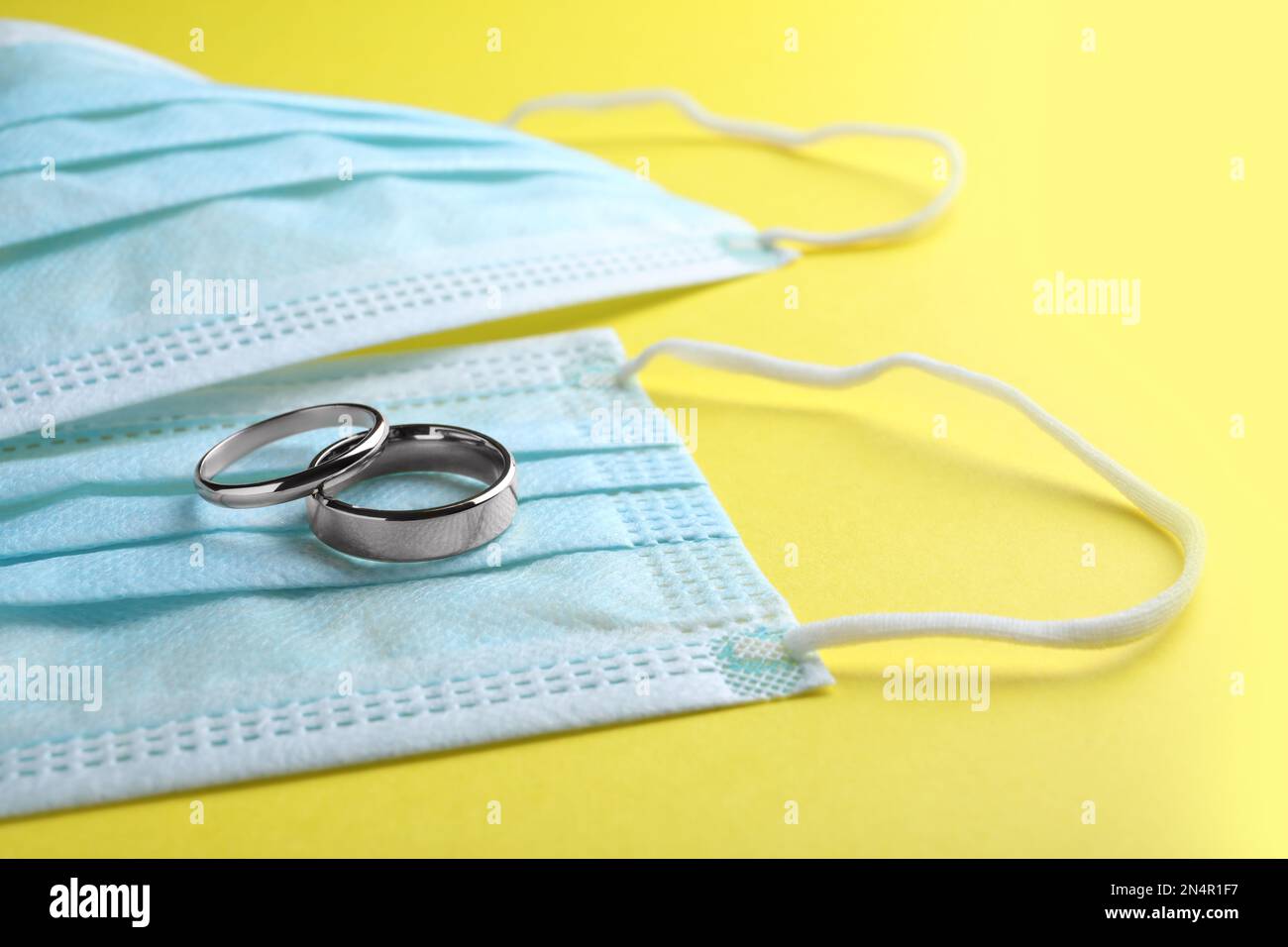 Protective masks and wedding rings on yellow background. Divorce during ...