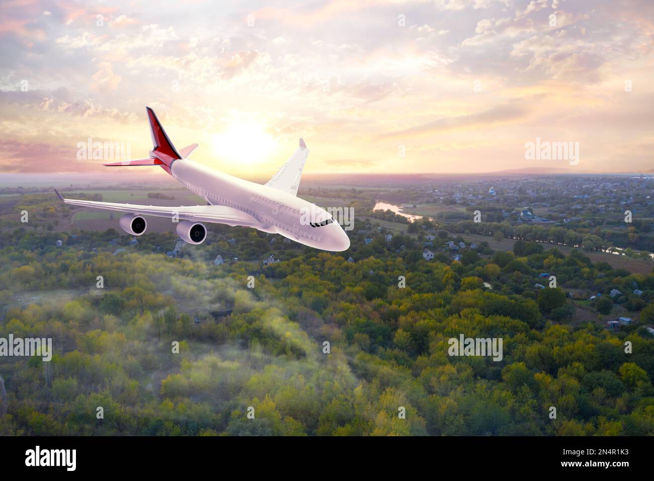 Modern airplane flying in cloudy sky over wood Stock Photo - Alamy