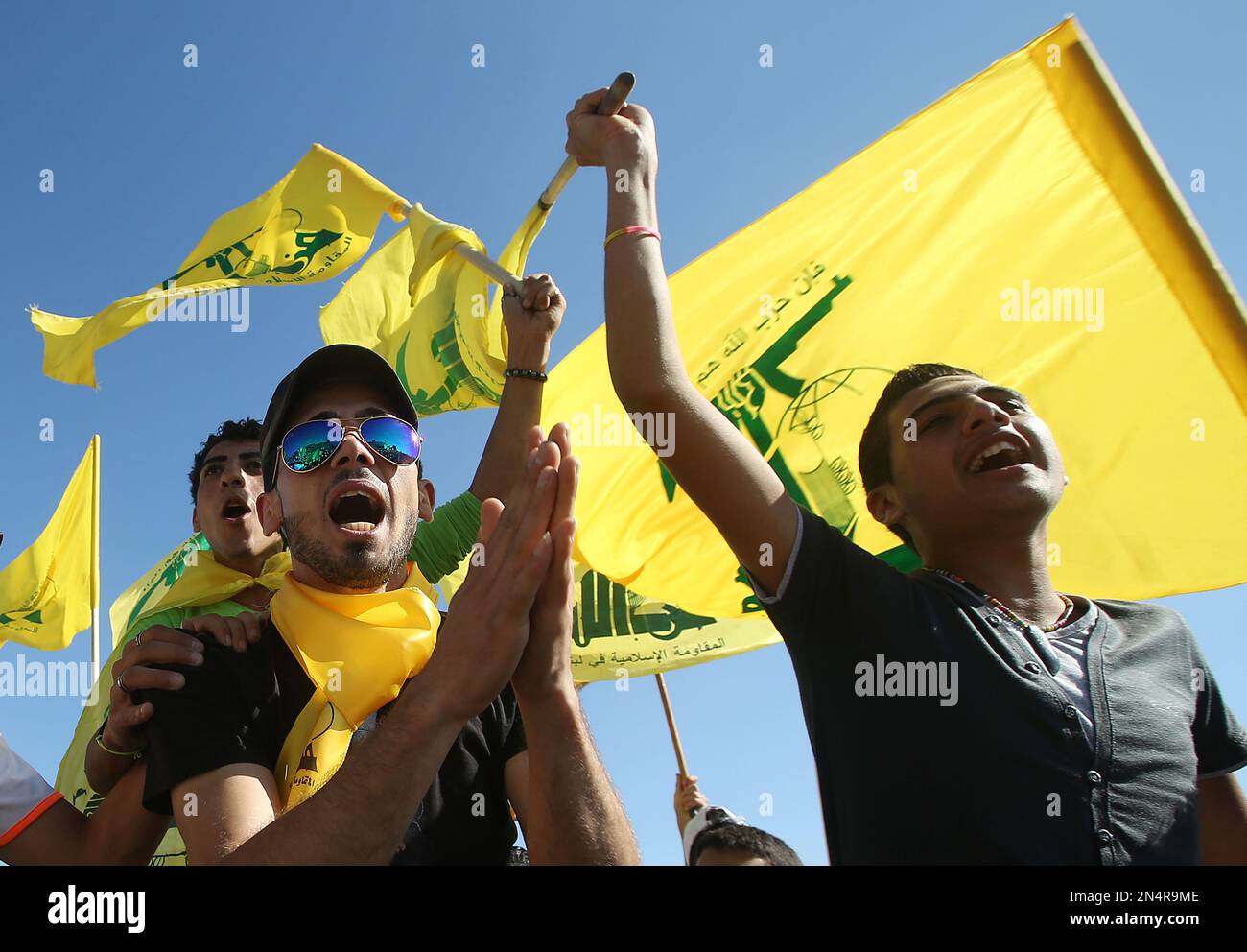 Hezbollah supporters shout slogans and wave Hezbollah flags, during a ...