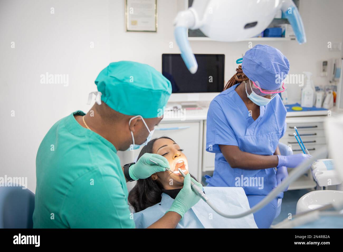 An African dentist checks the oral health of his patient while his ...