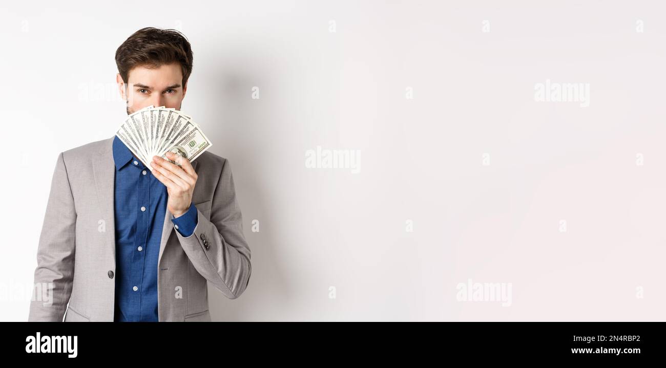 Rich businessman in suit showing dollar bills, hiding face behind money ...