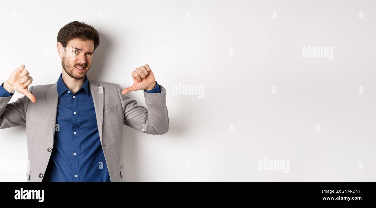 It sucks. Man feeling awkward showing thumbs down and judging something ...