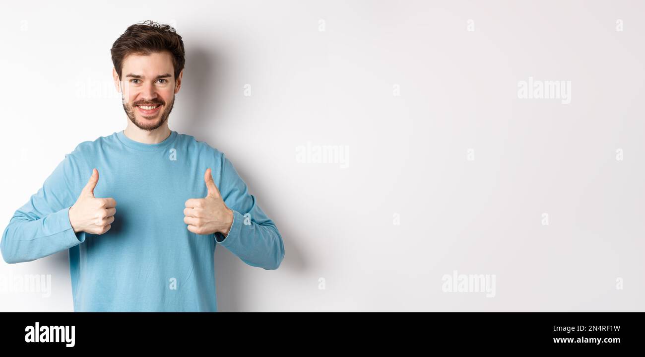 Smiling handsome man showing thumbs up, like and approve good choice ...