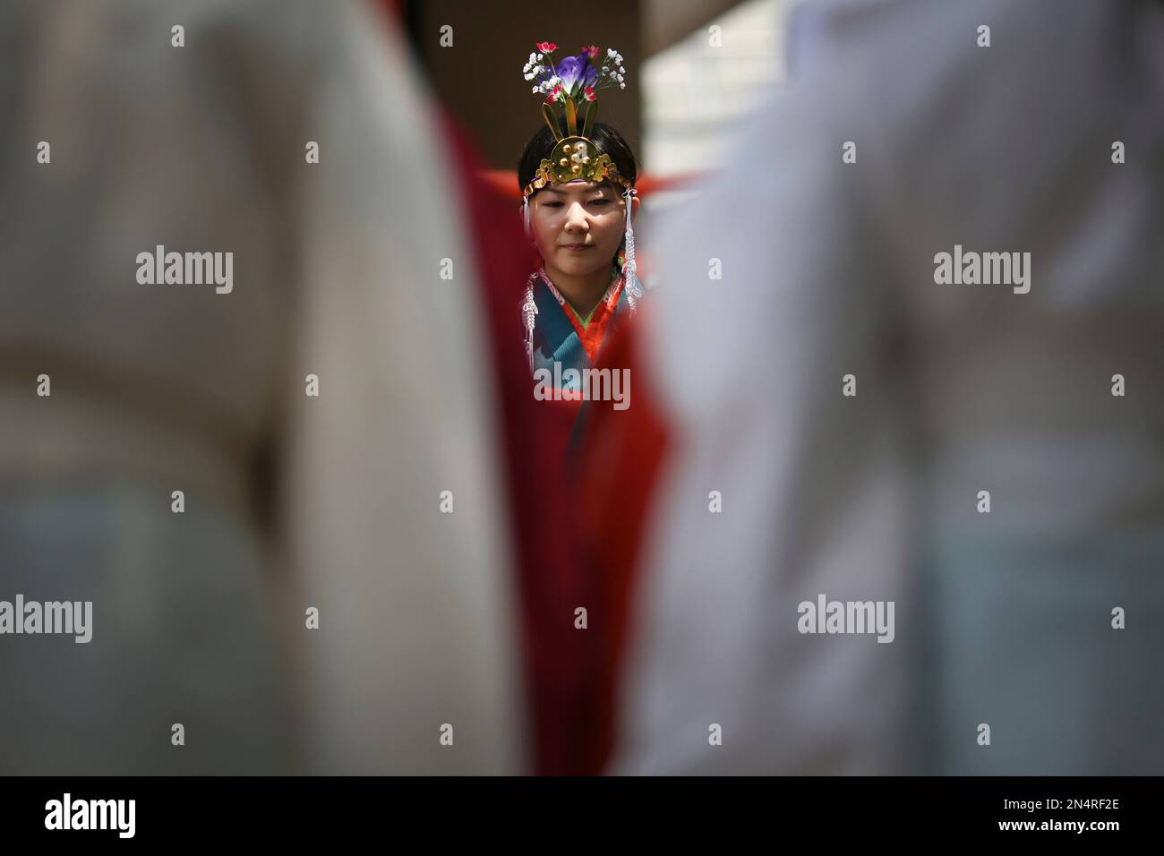 A shrine maiden in ritual clothing stands during a ceremonial rite for ...