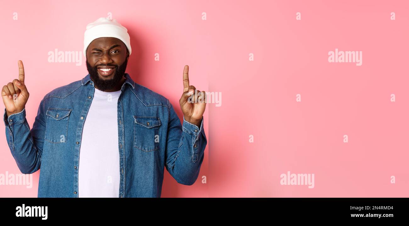 Cheeky african american man smiling and winking, showing deal on top ...