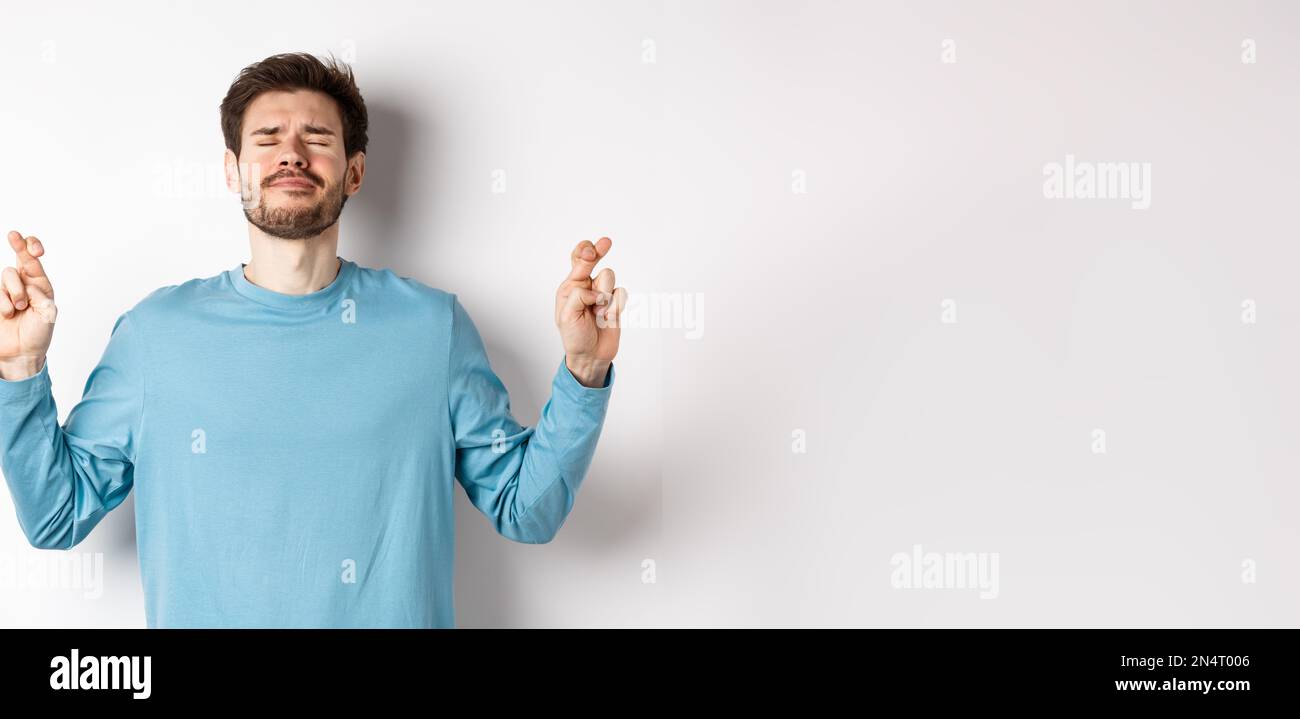 Worried hopeful man praying, cross fingers for good luck with eyes ...