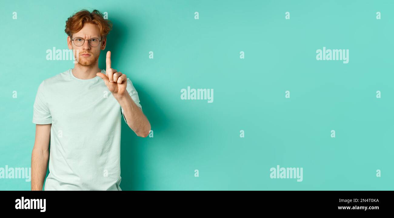 Angry and serious young man with red hair, wearing glasses, showing ...