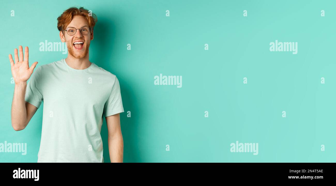 Friendly bearded guy in glasses saying hello, waving hand to greet and ...