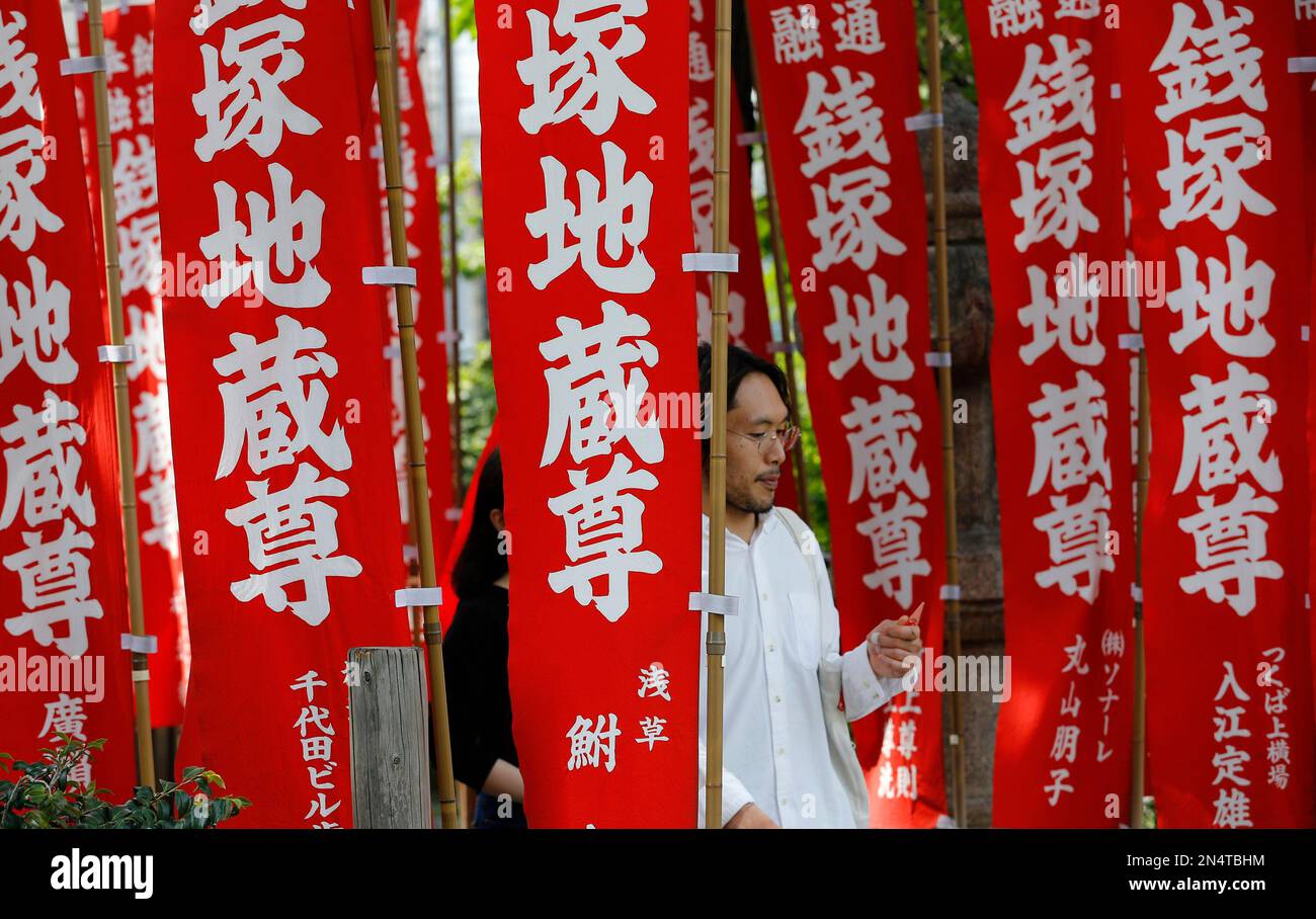 A couple walks between banners of guardian deity of children erected at ...
