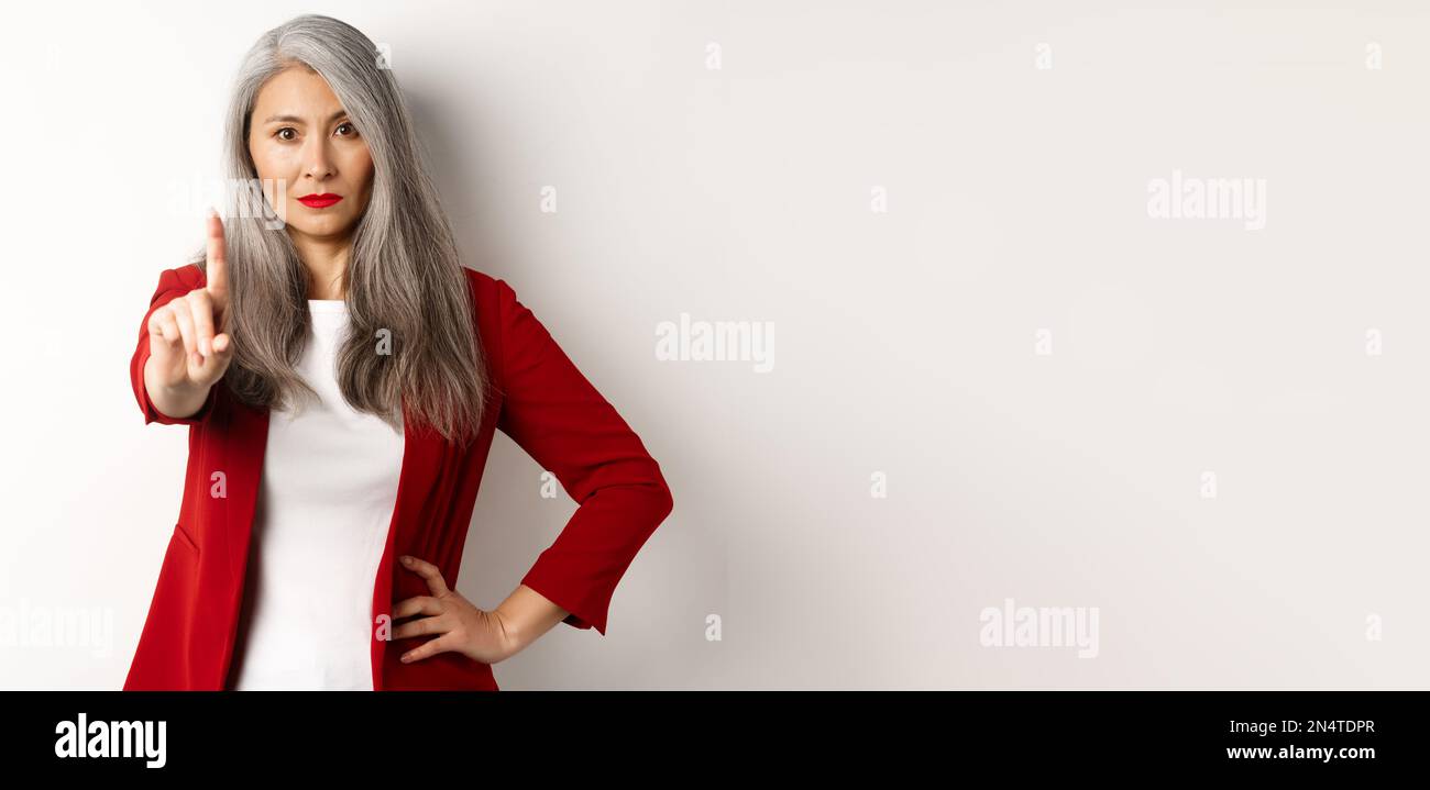 Serious and disappointed asian businesswoman showing stop gesture ...