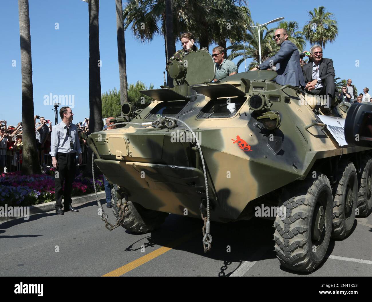 From left, Dolph Lundgren, Jason Statham and Harrison Ford ride a tank ...