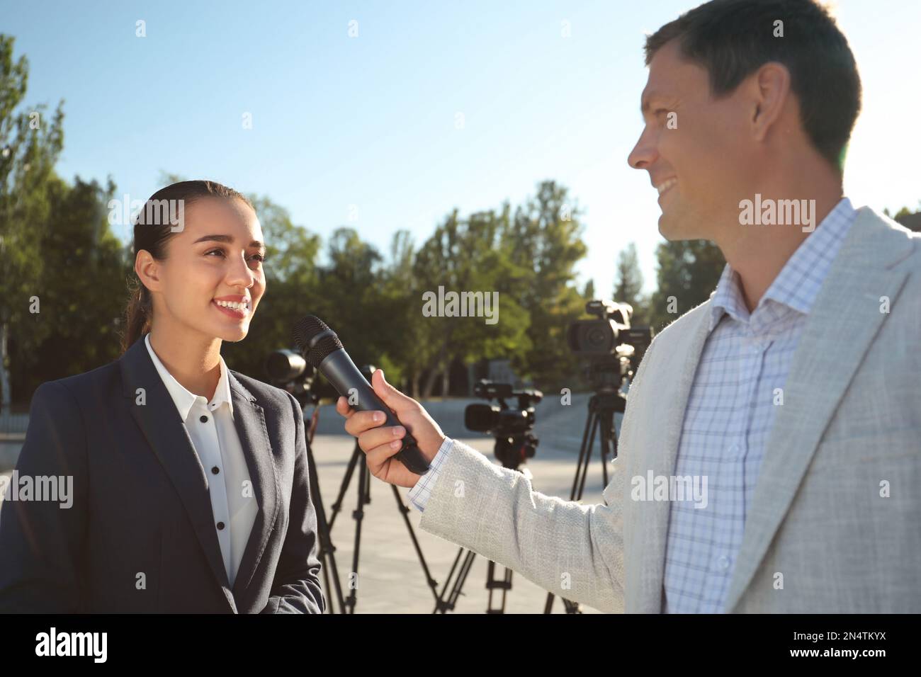 Professional journalist interviewing young woman on city street Stock ...