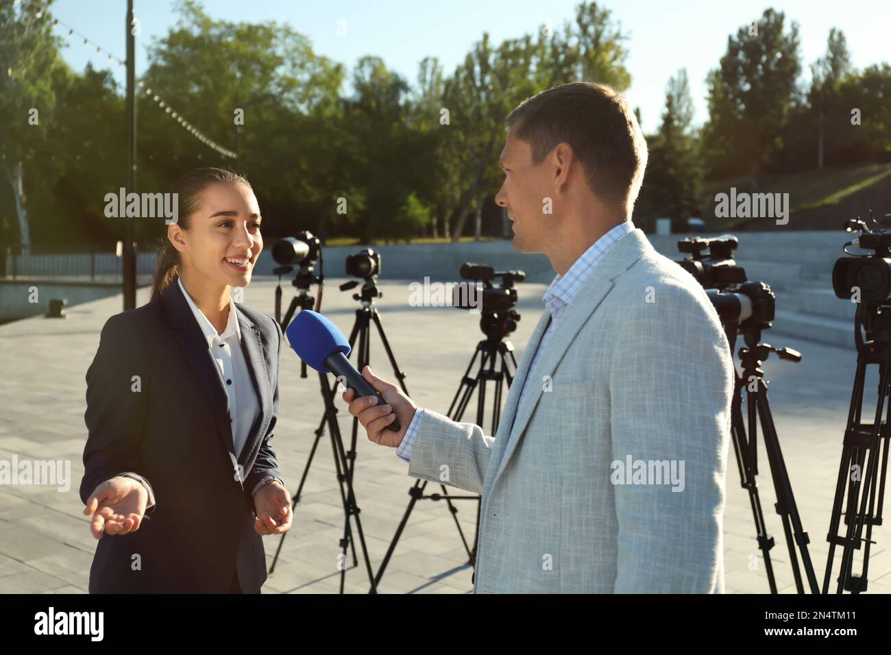 Professional journalist interviewing young woman on city street Stock ...