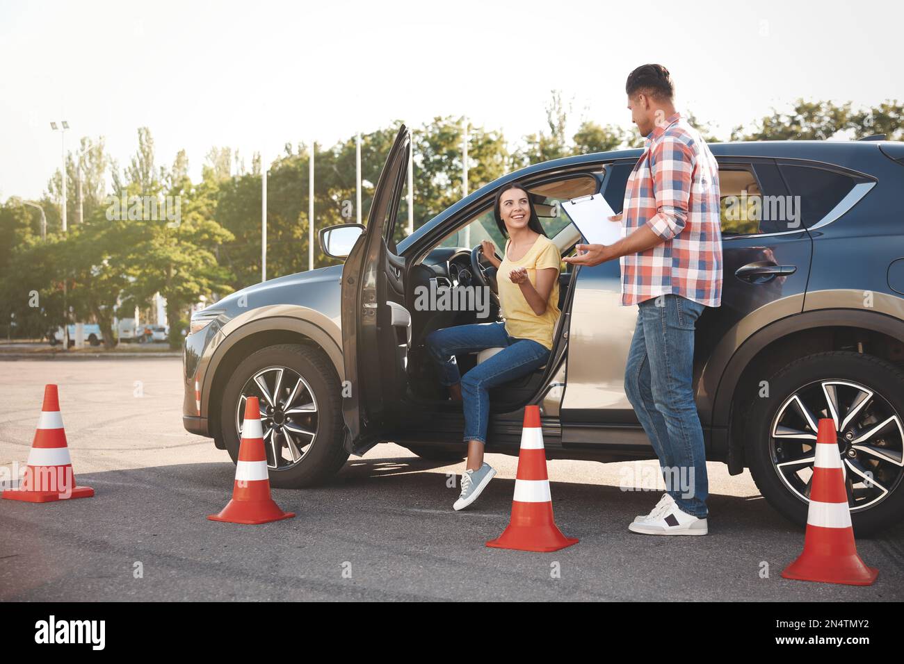 Instructor with clipboard and his student near car outdoors. Driving ...