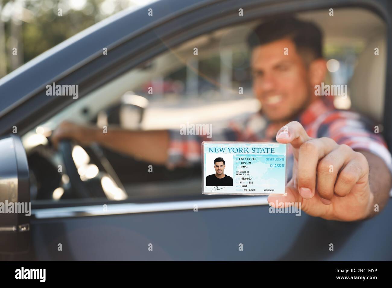 Happy man holding license while sitting in car outdoors, focus on hand ...