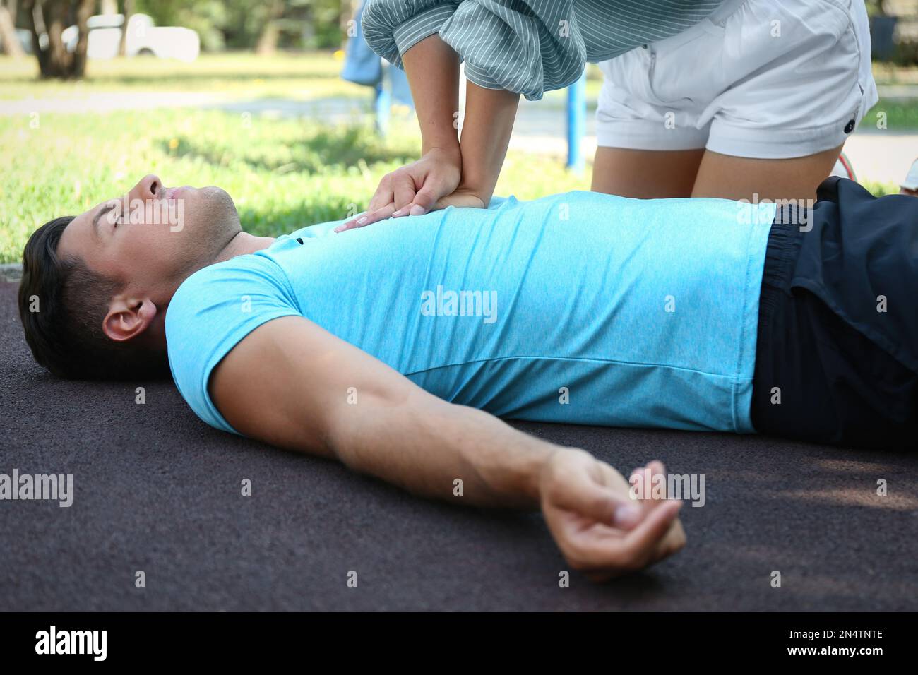Young woman performing CPR on unconscious man outdoors. First aid Stock ...