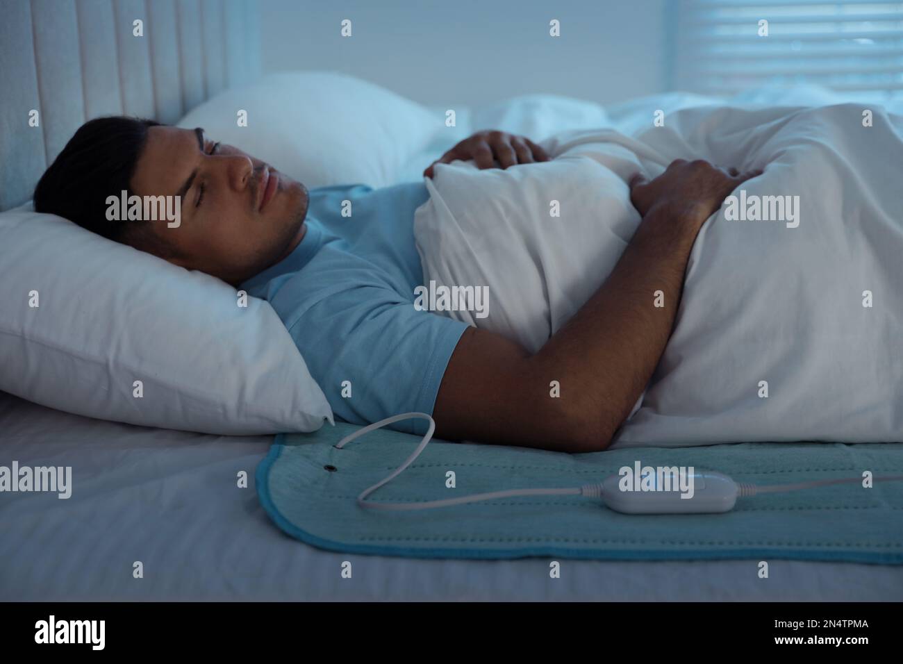 Man sleeping on electric heating pad in bed at night Stock Photo - Alamy
