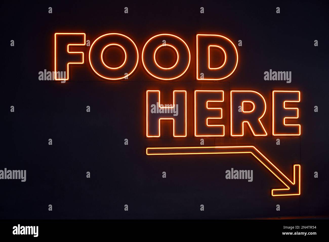Illuminated sign saying: 'Food Here' with an arrow underneath to point ...