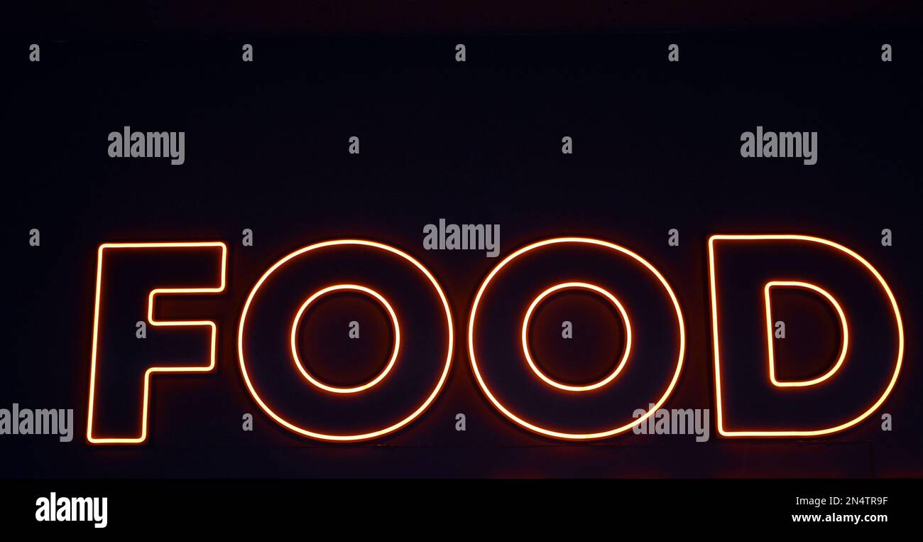 Illuminated sign saying: 'Food Here' on a dark background in a retail ...