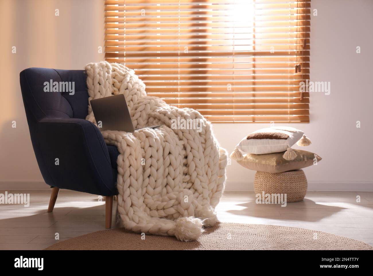 Soft knitted blanket and modern laptop on armchair in room. Interior ...