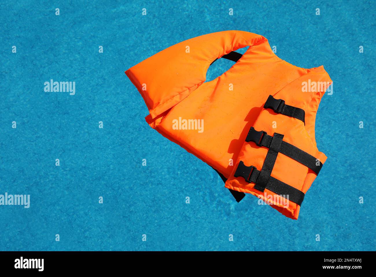 Bright orange life jacket floating in swimming pool Stock Photo - Alamy