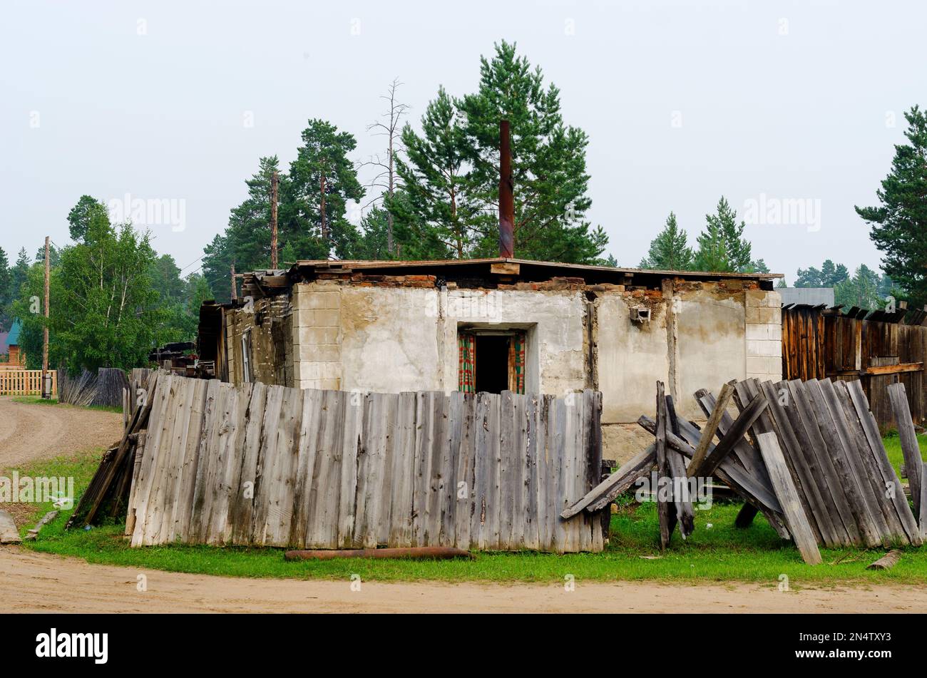 An old, rickety wooden barn stands with an open door behind a fallen ...
