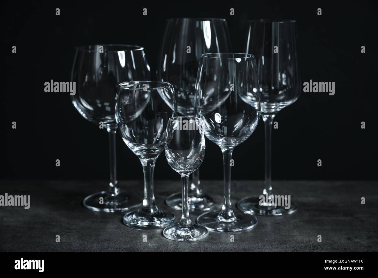 Set of bar glassware on table against dark background Stock Photo - Alamy