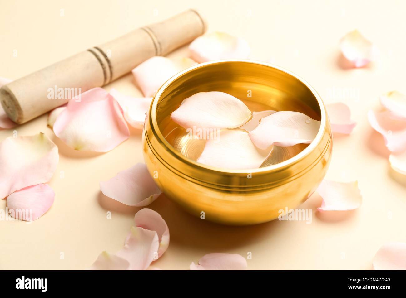 Golden singing bowl with petals and mallet on beige background. Sound ...
