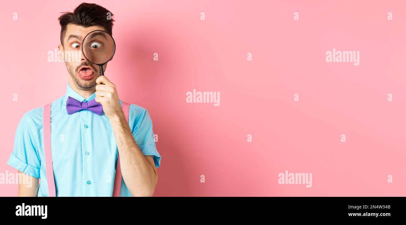 Funny man in bow-tie look through magnifying glass, squinting and ...