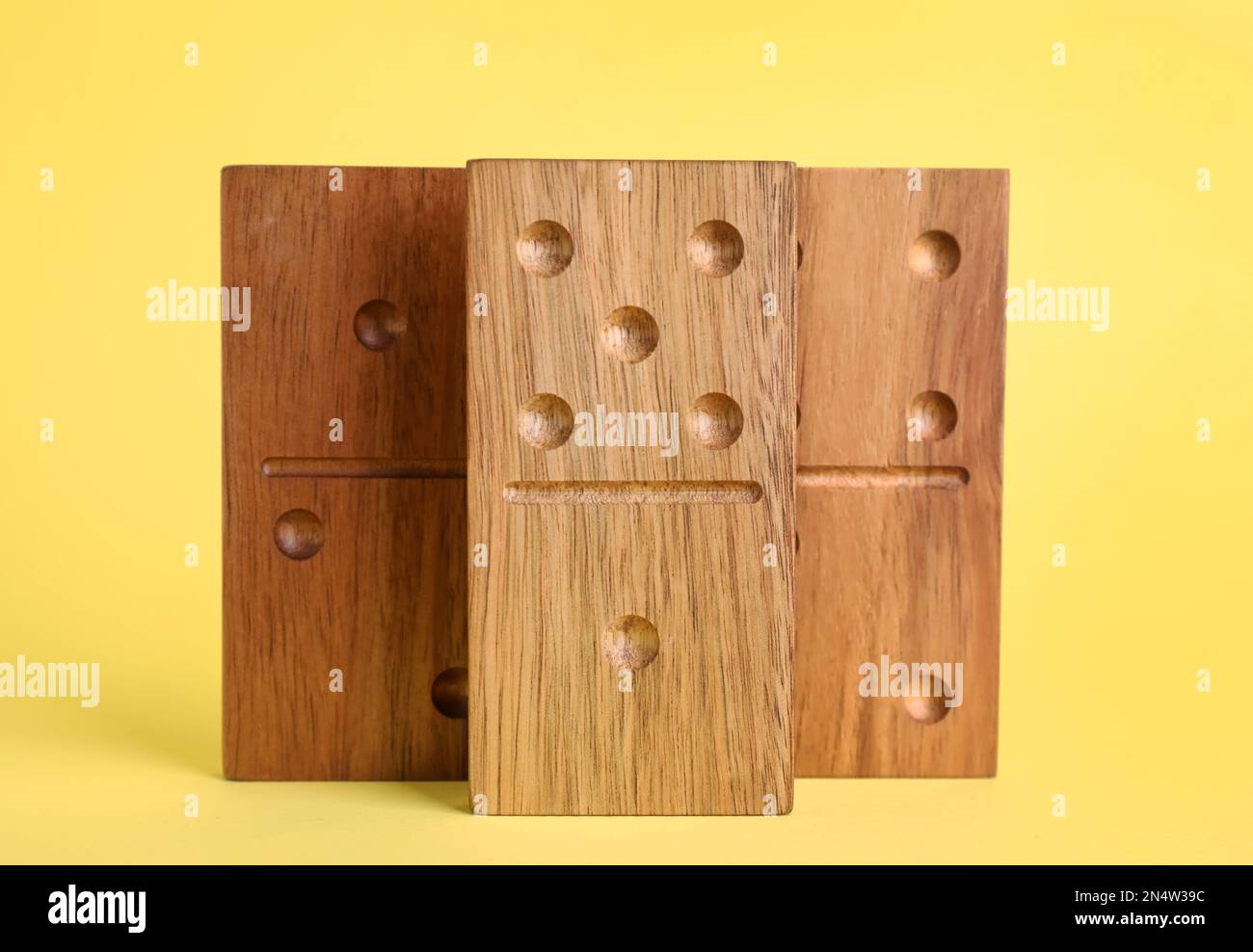 Wooden domino tiles with pips on yellow background Stock Photo - Alamy