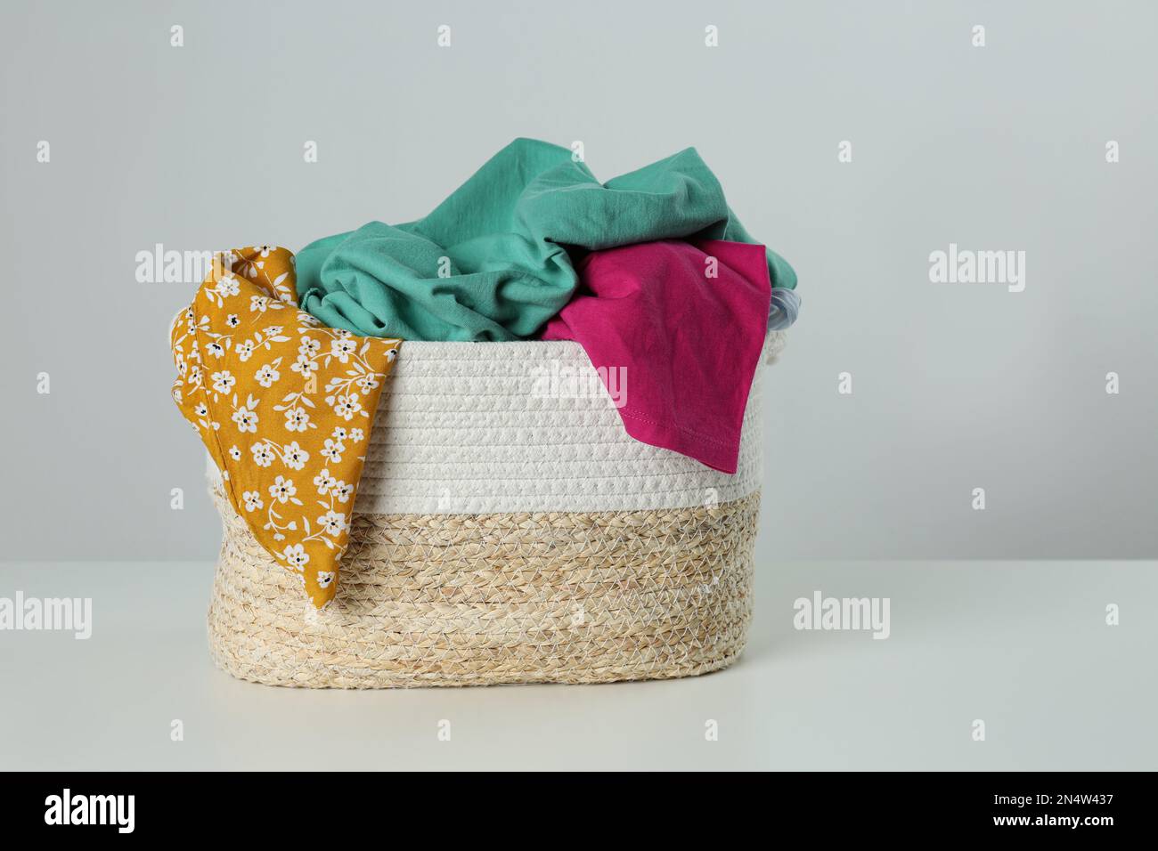 Wicker laundry basket with different clothes on light background Stock ...