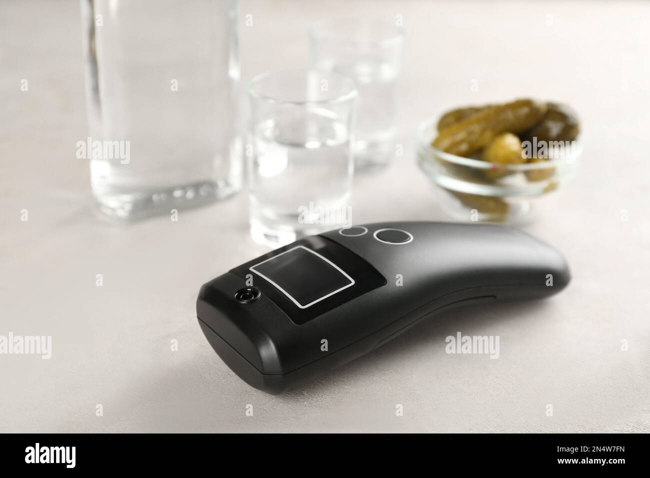 Modern breathalyzer and vodka on white table Stock Photo - Alamy