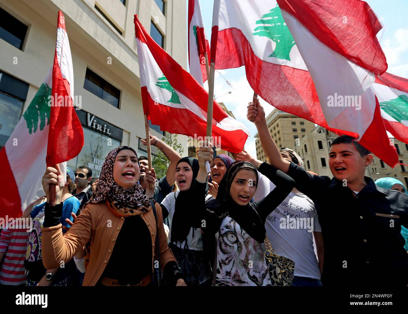 Lebanese protesters hold national flags and chant slogans as thousands ...