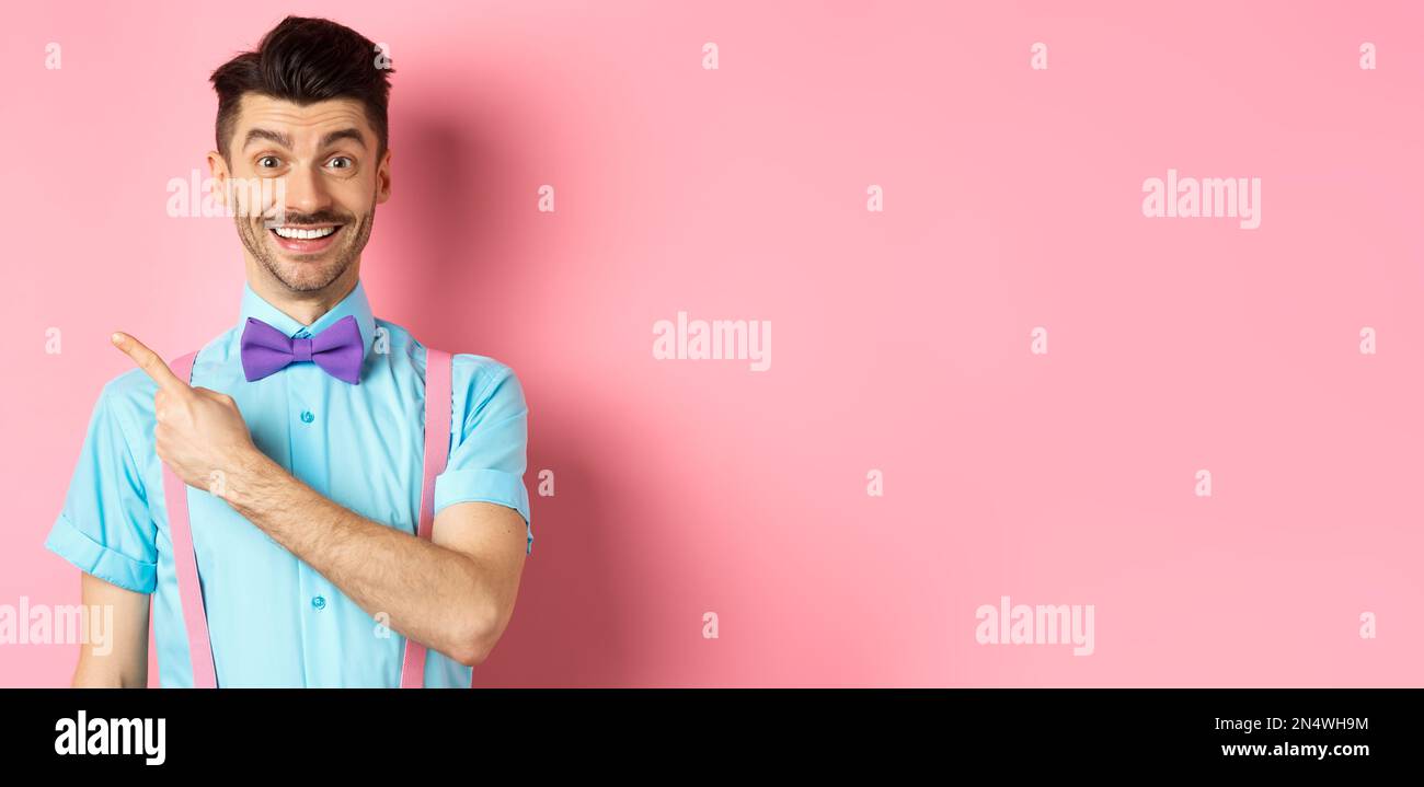 Portrait of handsome happy man showing logo, pointing left and smiling ...