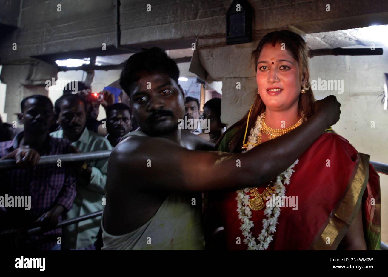 A temple priest ties a holy string around the neck of a eunuch as a ...