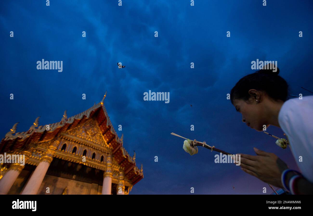 A Thai Buddhist carrying a lotus bud prays in front of Marble Temple in ...