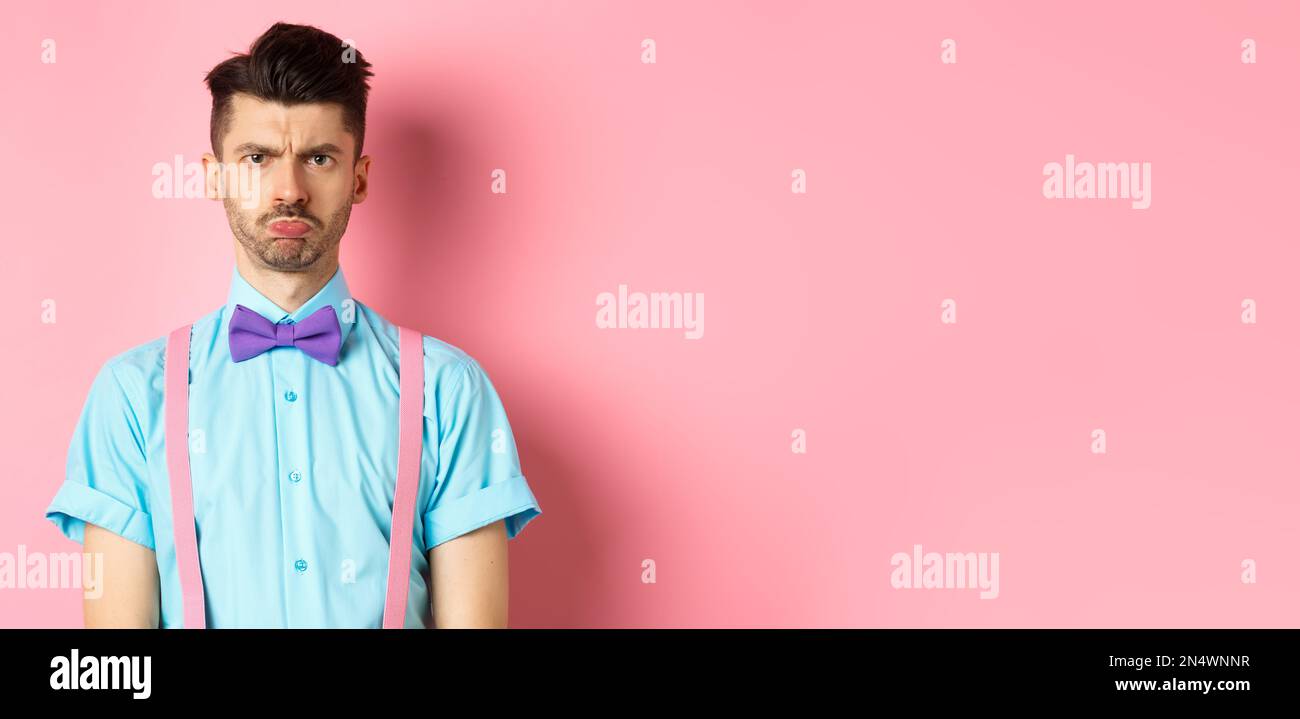 Sad and offended young man, frowning and pucker lips, looking angry at ...