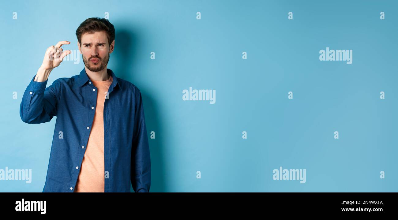 Confused guy showing small size and looking doubtful or skeptical ...