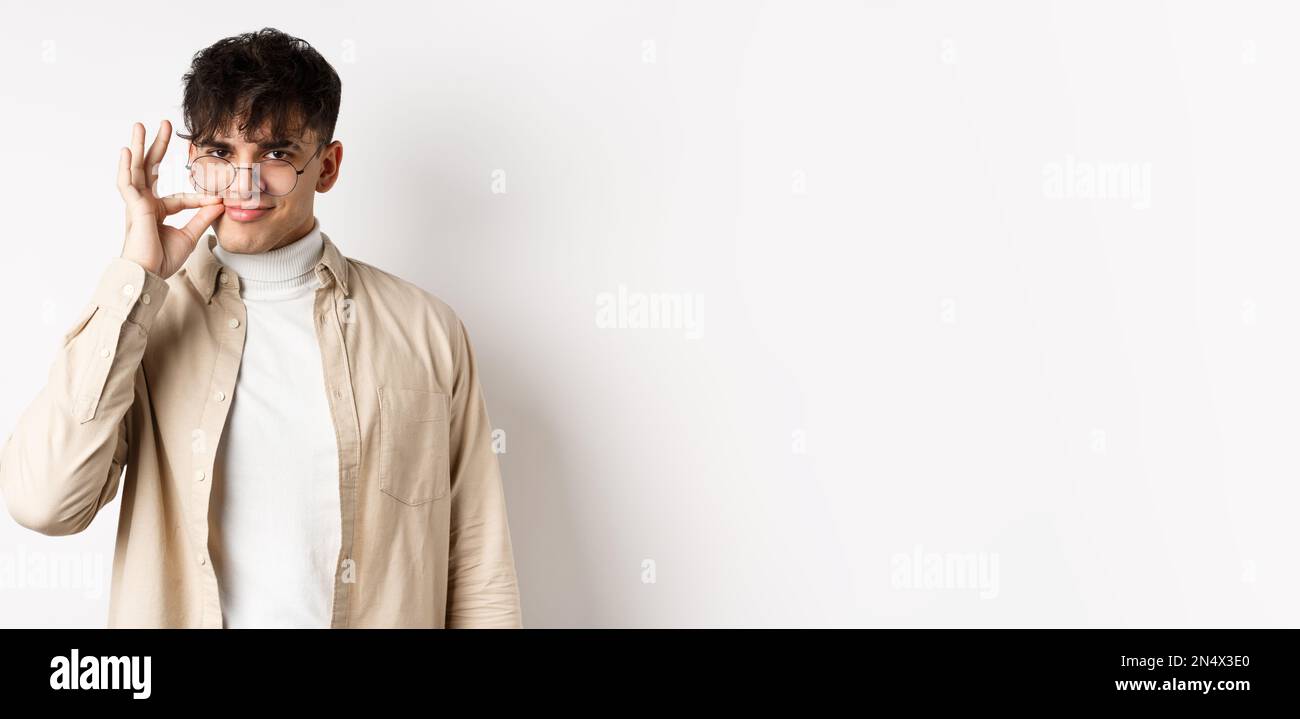 Smiling cunning guy in glasses shut his mouth on zipper, showing seal ...