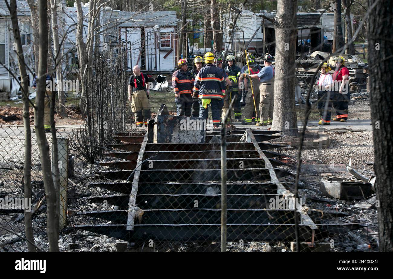 Firefighters stand near the remains of a trailer that was destroyed by ...