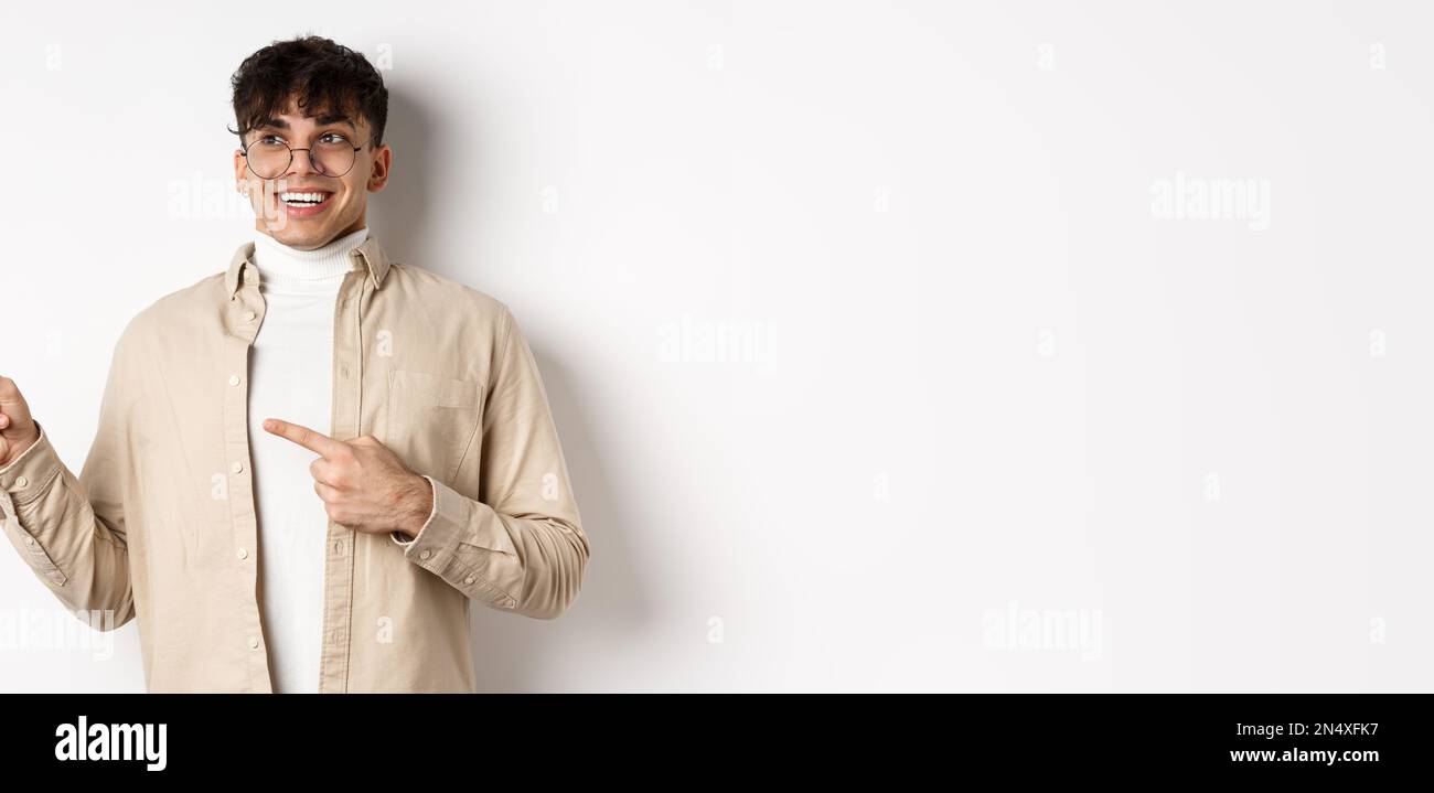 Excited and enthusiastic young man in glasses, pointing fingers and ...