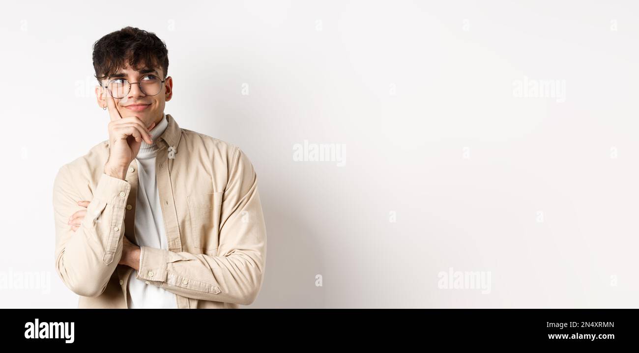 Image of happy dreamy young man imaging something good, smiling and ...