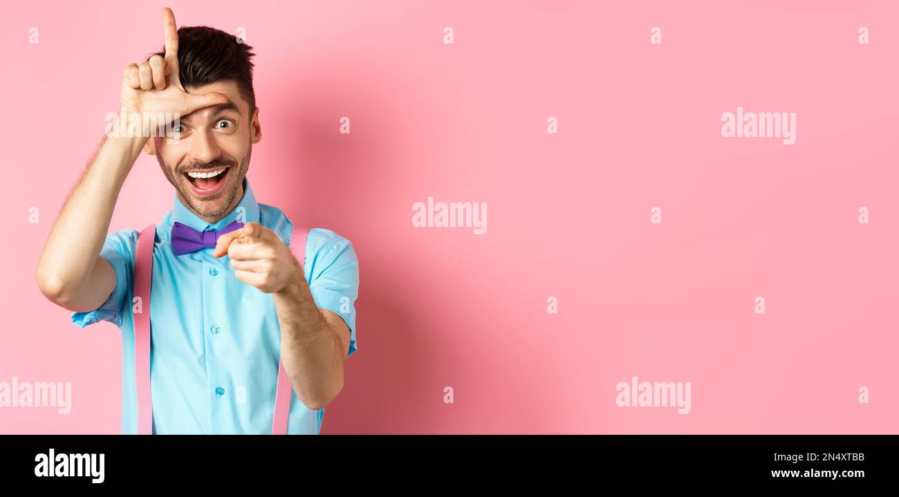 Image of funny guy pointing at you camera and showing loser sign ...