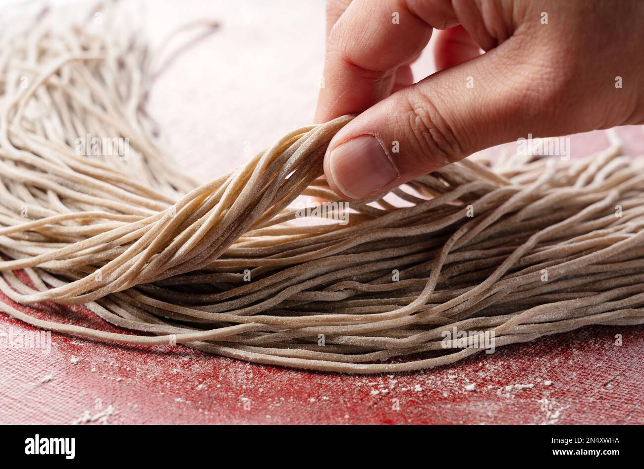 A man's hand holding raw soba noodles. Soba before boiling. Freshly ...