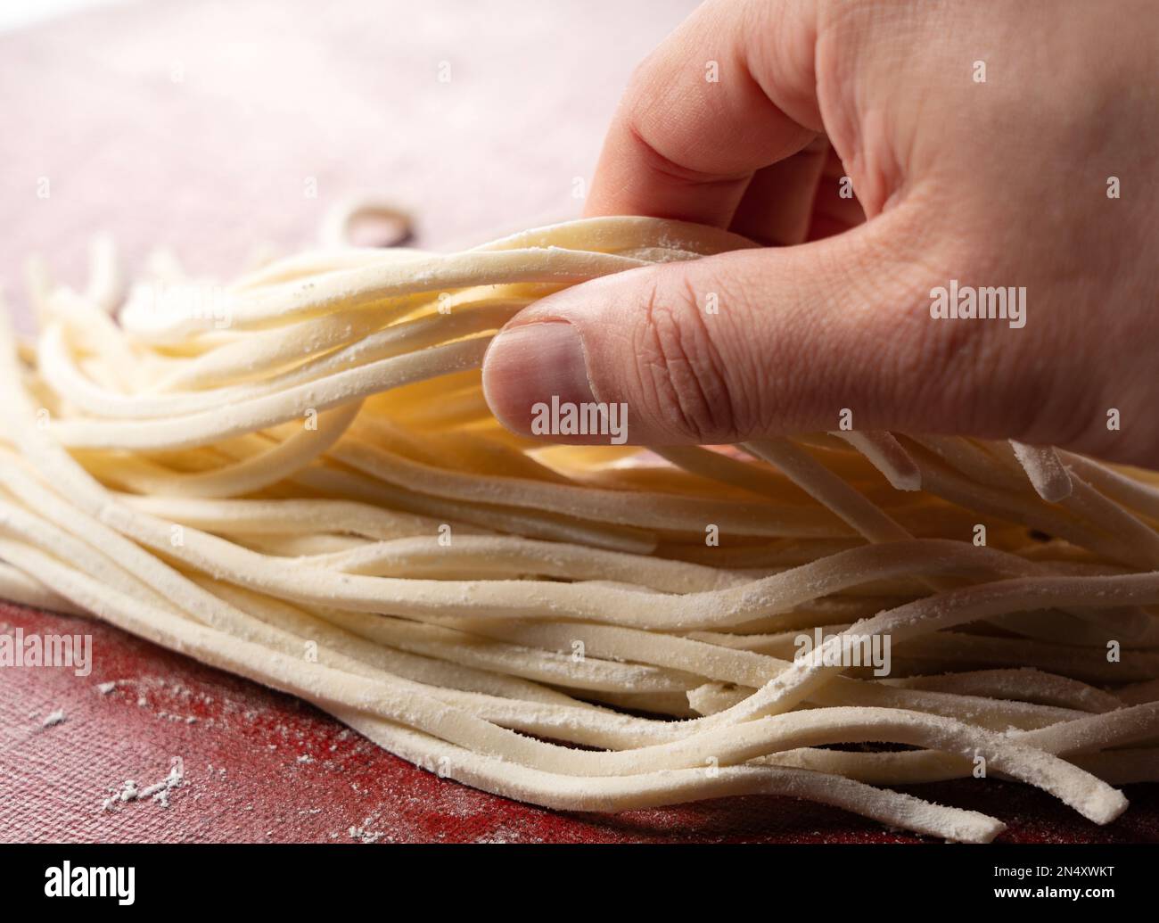 A man's hand holding fresh udon noodles. Udon noodles before boiling ...