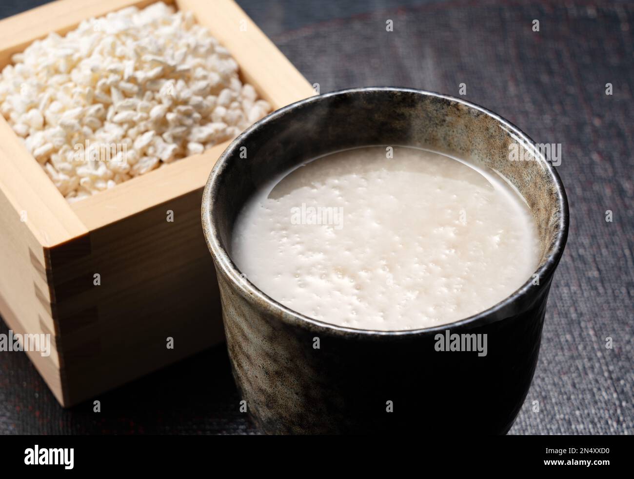 Amazake placed against a black background and rice koji in a masu box ...