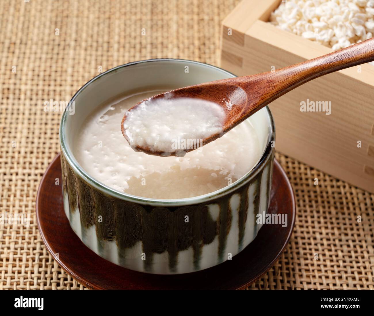Amazake and a wooden spoon on the table. Amazake is a traditional ...