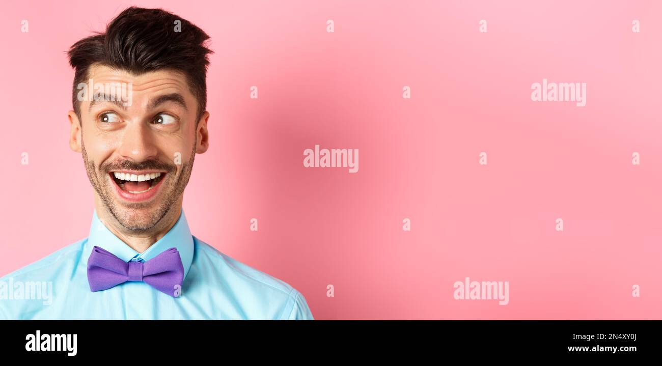 Close up of cheerful smiling guy, looking aside at logo with happy face ...