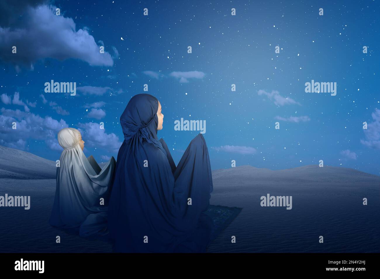 Asian Muslim mother and daughter in a hijab raised hands and praying ...